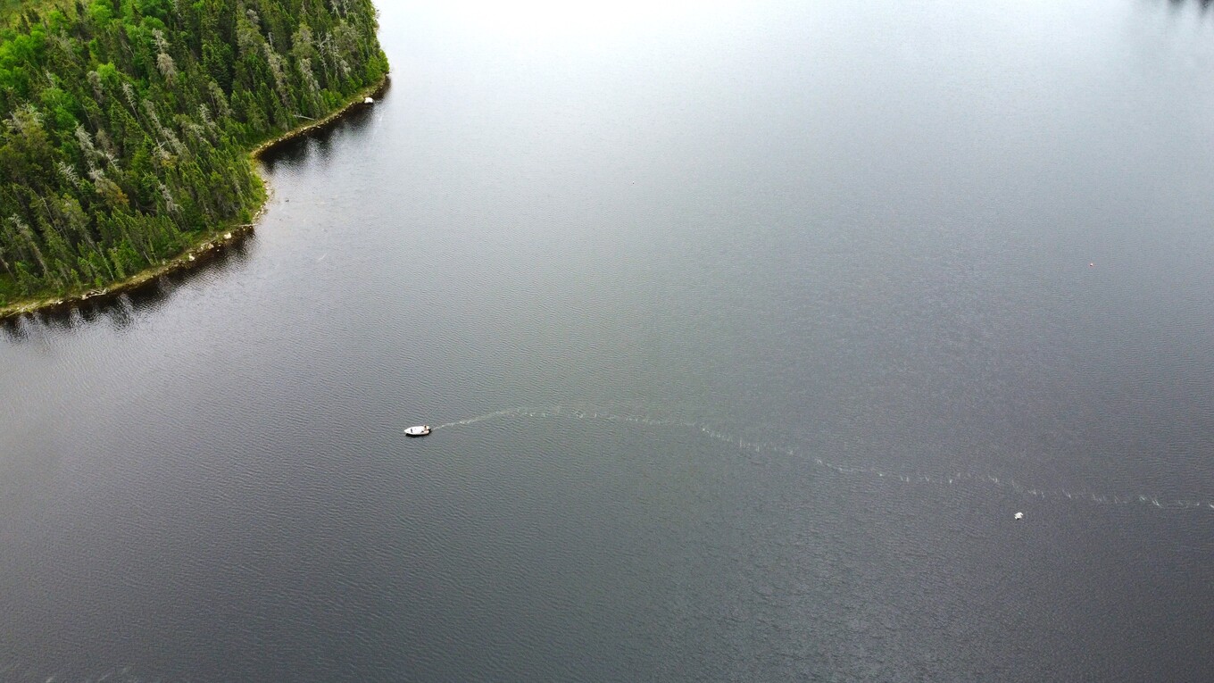 Aerial shot of a boat driving across a lake | IISD Experimental Lakes Area